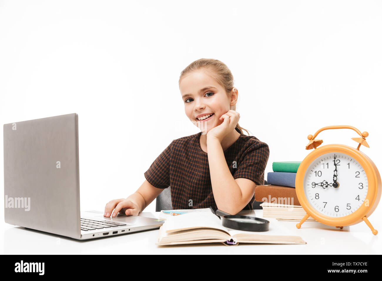 Portrait of adorable school girl using silver laptop while studying and ...