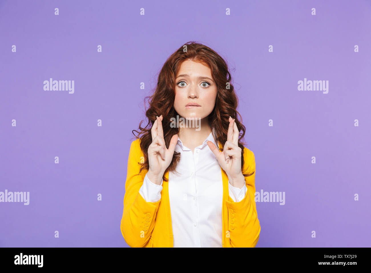 Portrait of a pretty worried young redheaded woman standing isolated ...
