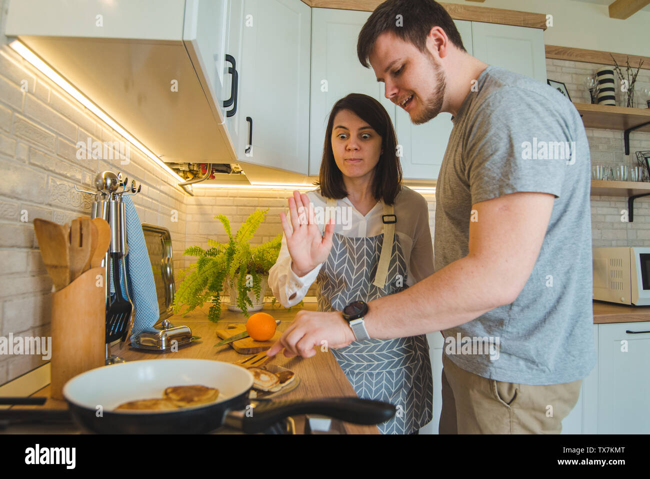 man steals food while woman making breakfast. copy space. domestic ...