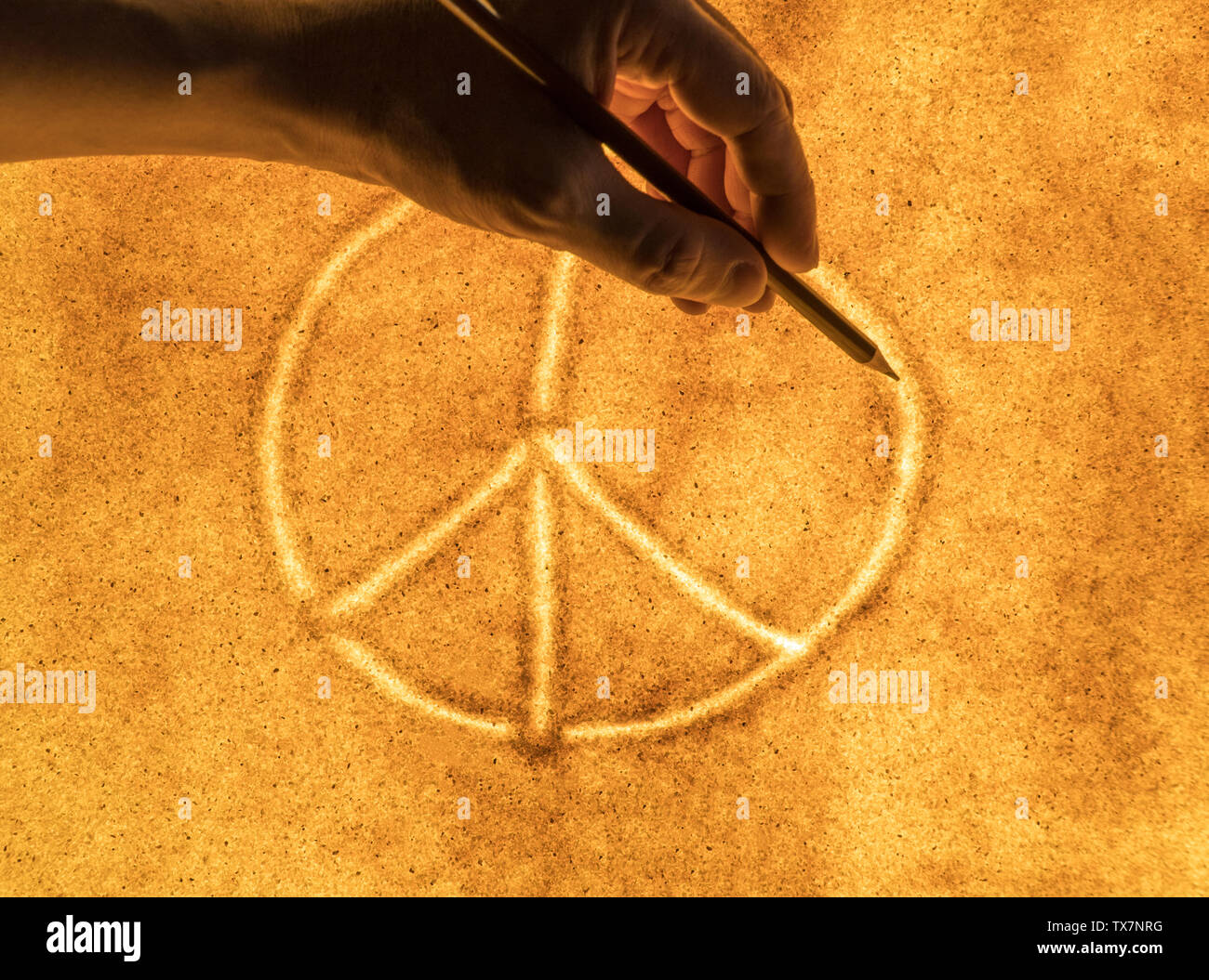 the hands of men draw in the sand the international symbol of peace ...