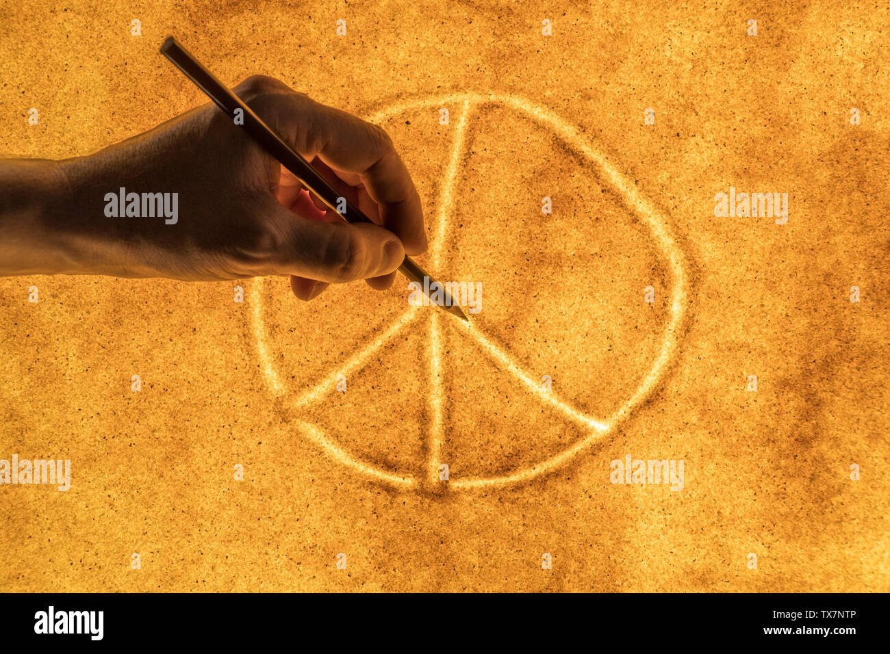 the hands of men draw in the sand the international symbol of peace ...