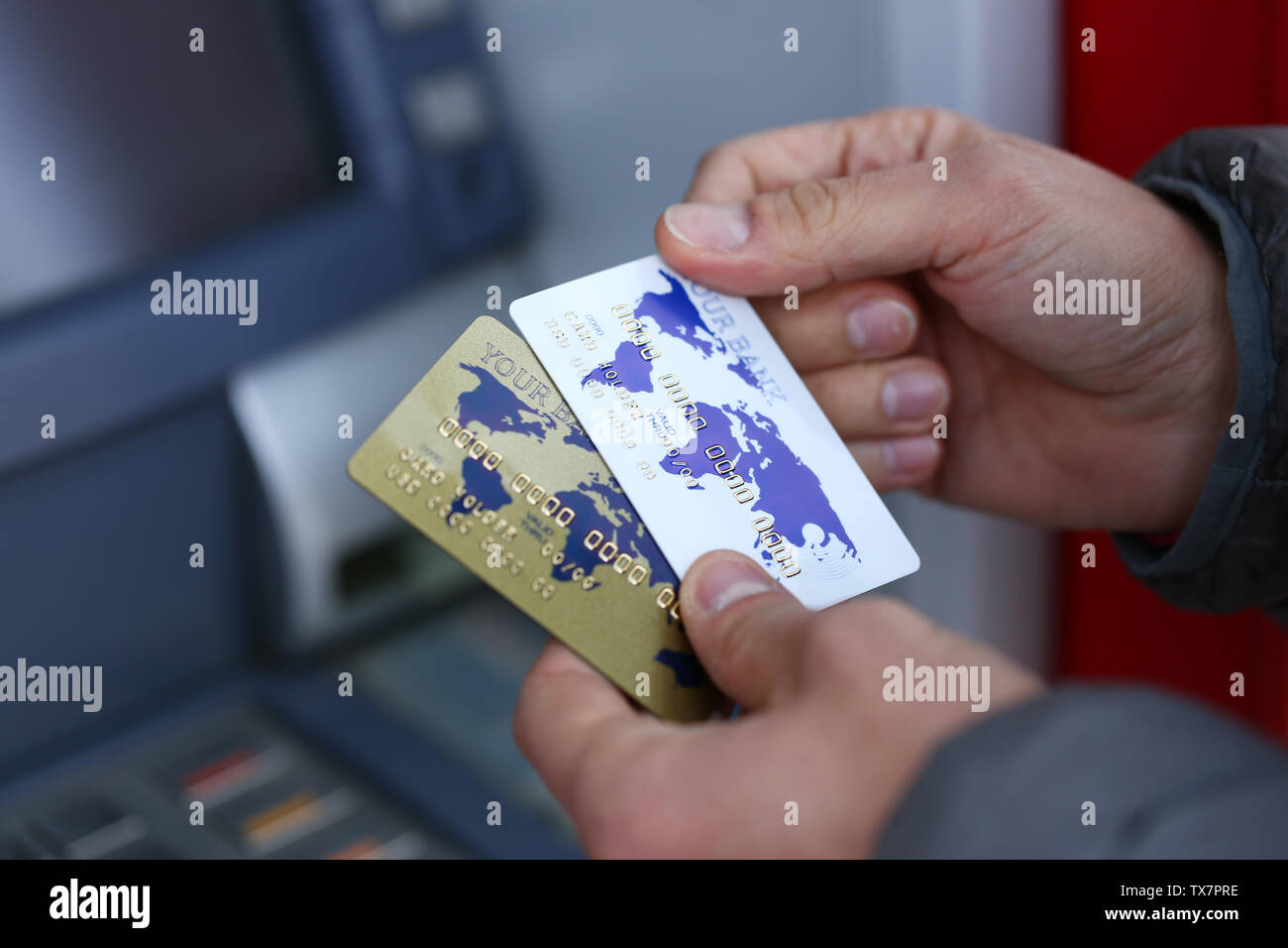 Male hand hold white and gold credit card aganist ATM background Stock ...