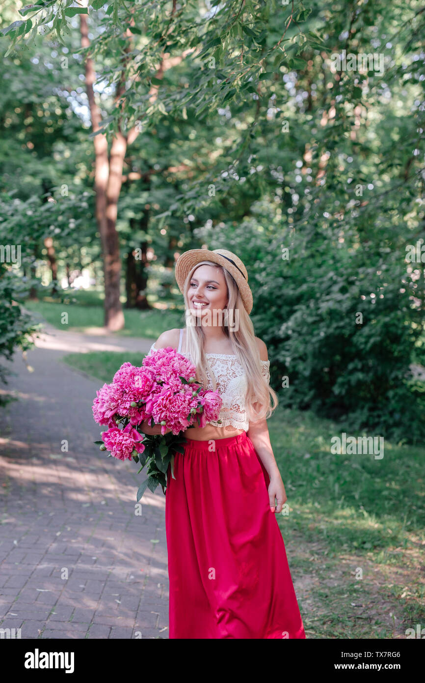 Beautiful woman in straw hat with peony flowers. Girl wearing a pink ...