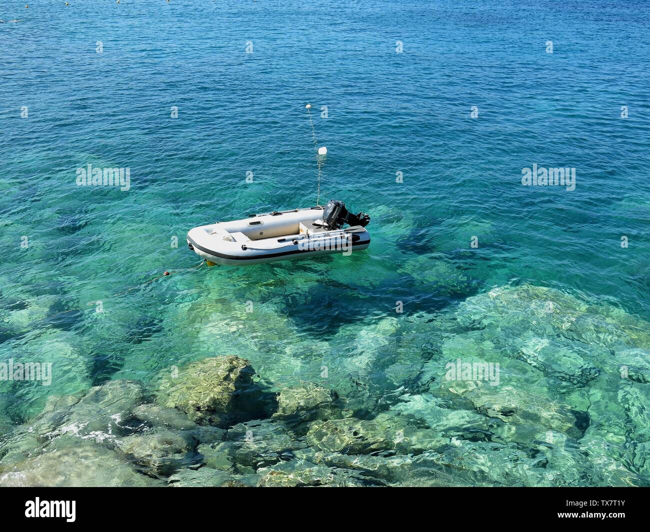 Inflatable motor boat anchored in crystal clear water at Agia Pelagia ...