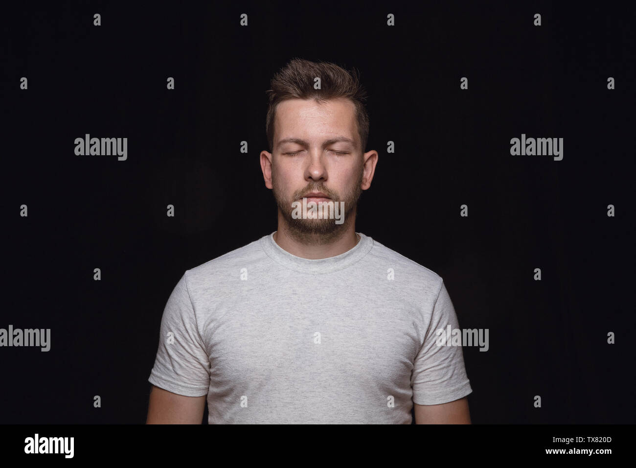 Close up portrait of young man isolated on black studio background ...