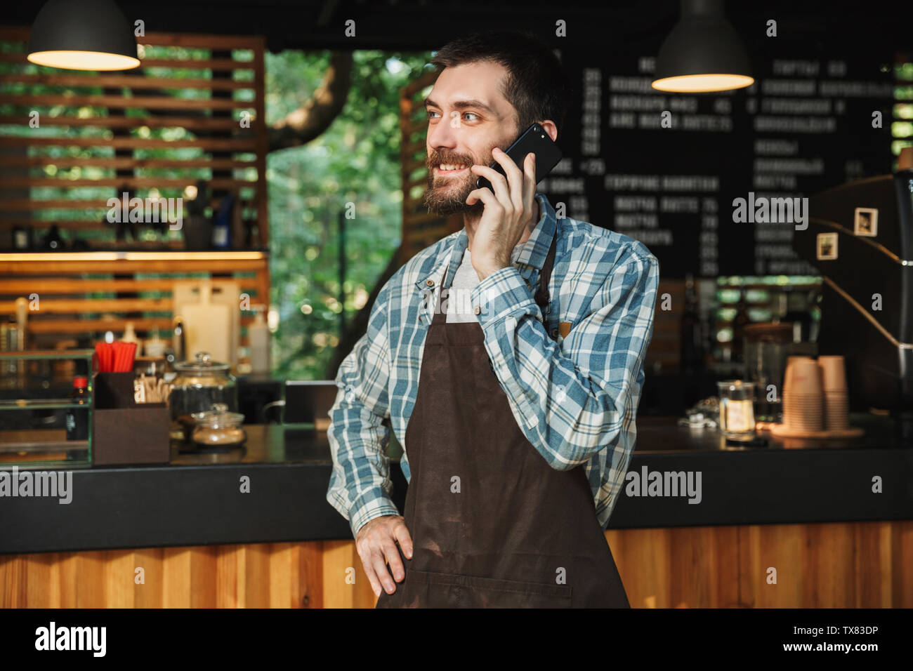Portrait of professional barista guy wearing apron smiling and talking ...