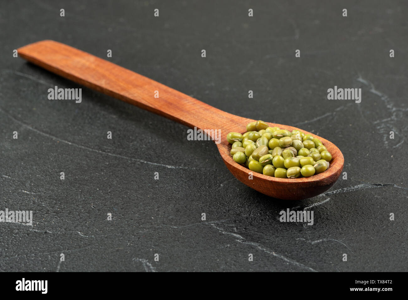 Wooden spoon with green mung beans on concrete background Stock Photo ...