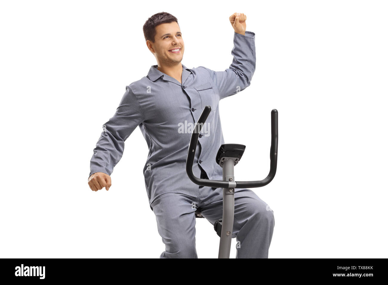Young guy in pajams stretching on an exercise bike isolated on white ...