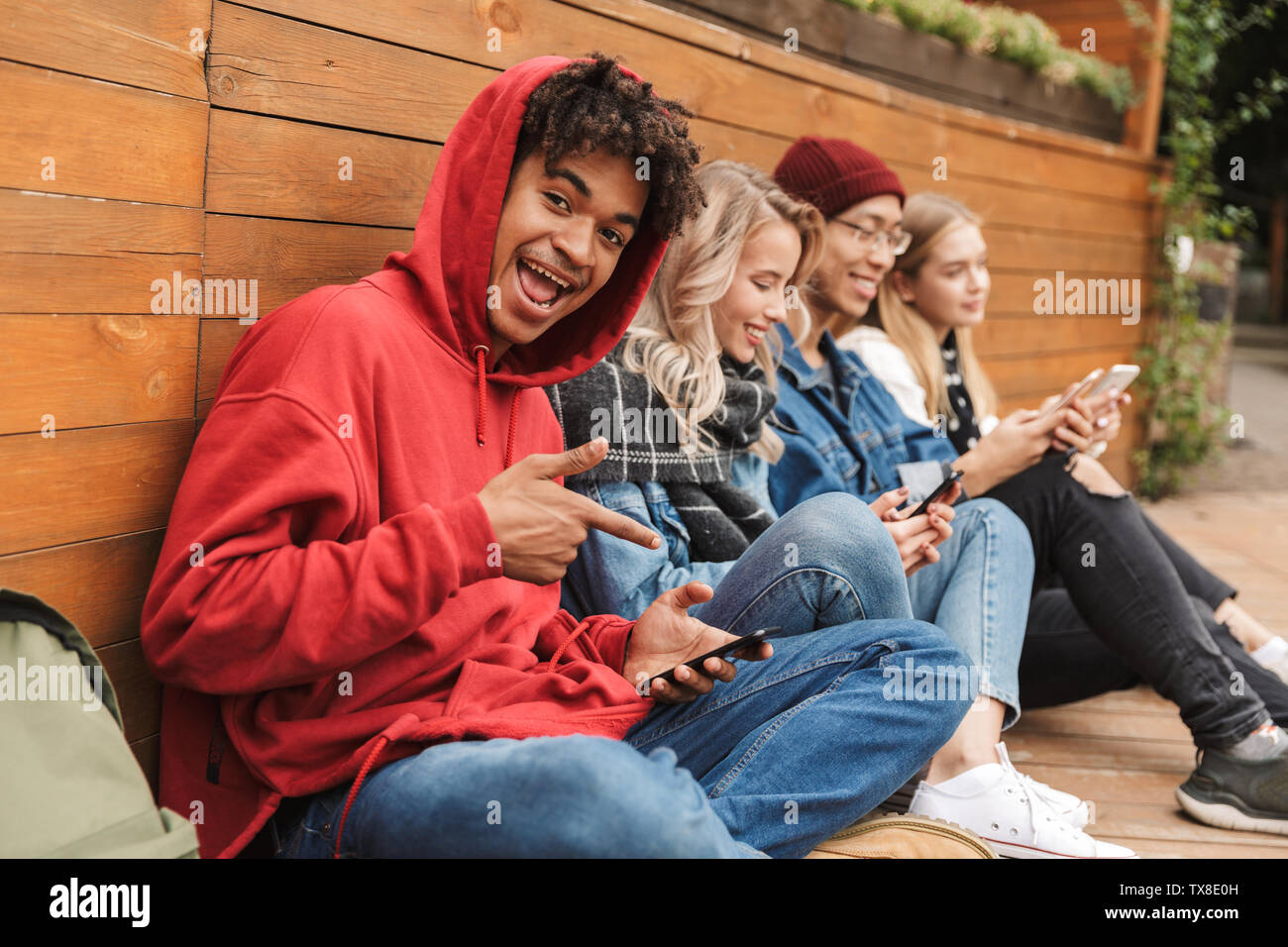 Happy multhietnic friends students hanging out together outdoors, using ...