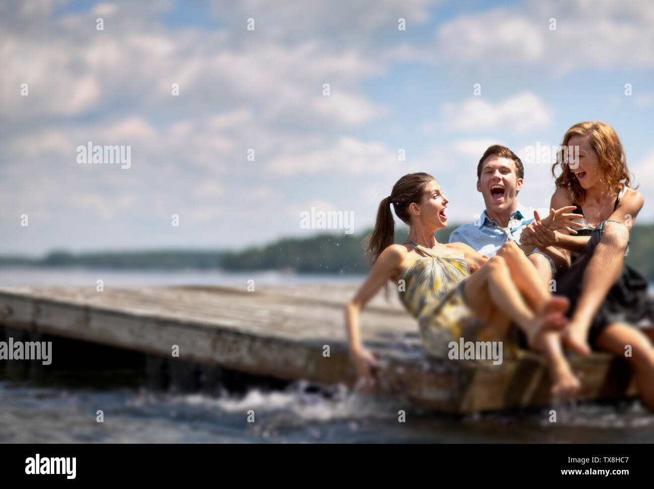 Three friends playing while dipping their feet in water Stock Photo - Alamy