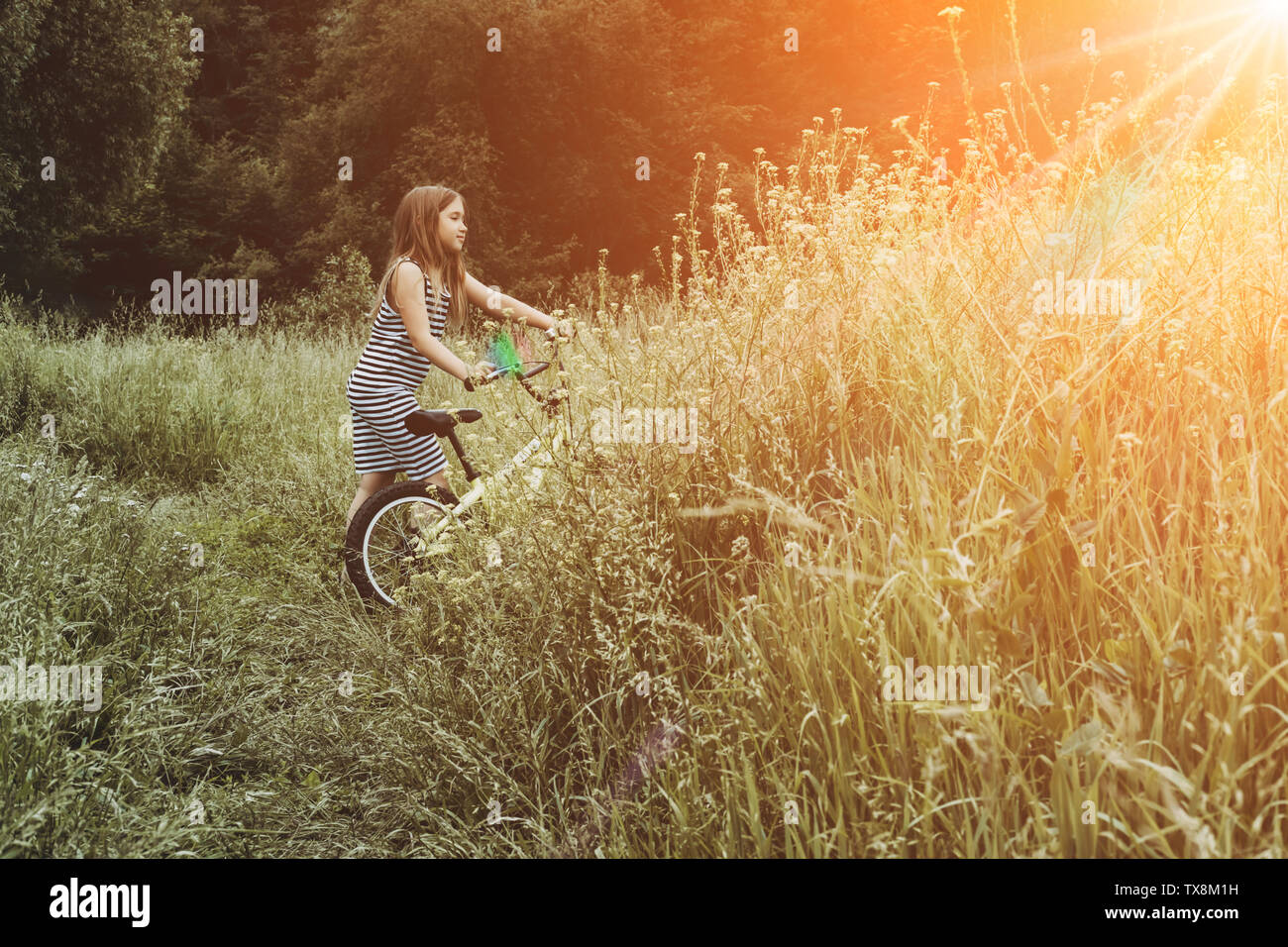 Girl in striped dress riding bike. Spending time outdoors. Child ...