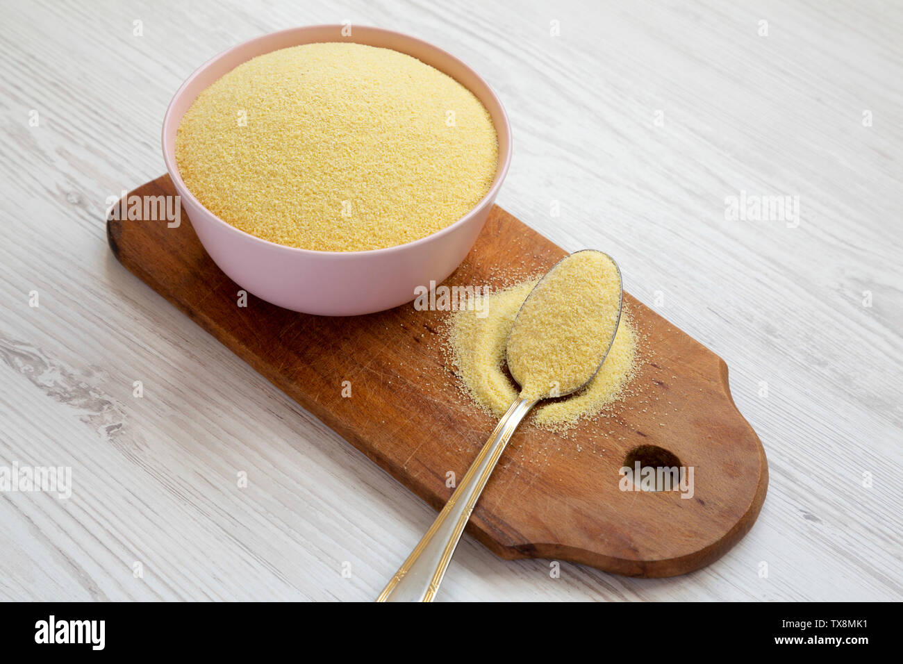 Dry semolina durum flour in a pink bowl over white wooden background ...