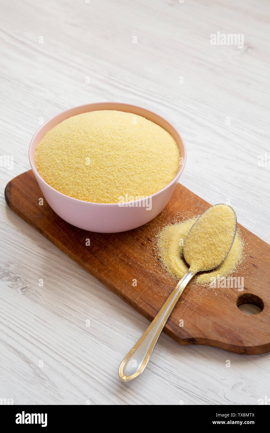 Dry semolina durum flour in a pink bowl over white wooden background ...