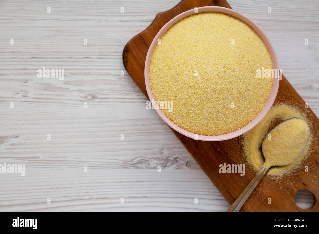 Dry semolina durum flour in a pink bowl over white wooden background ...