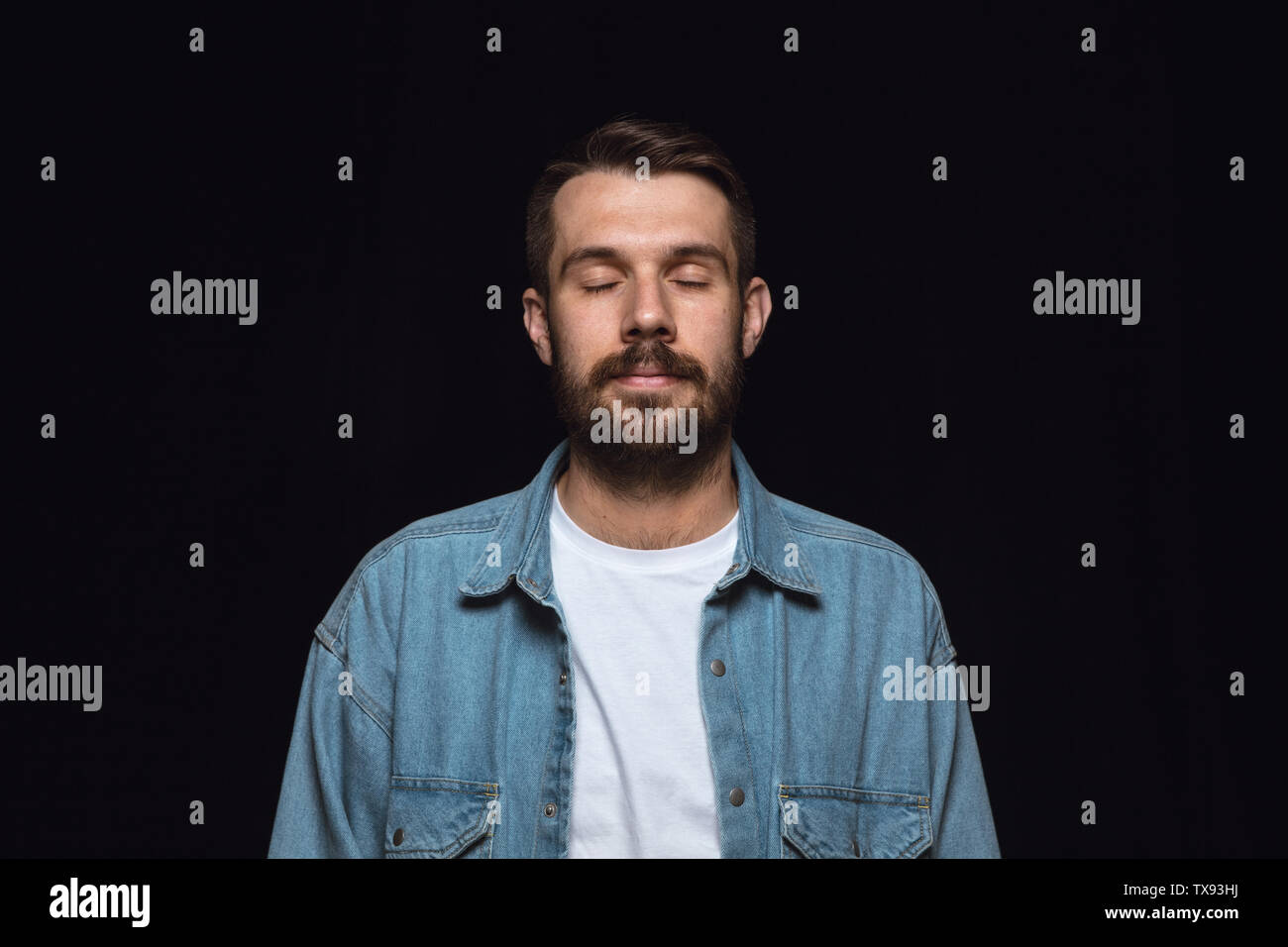 Close up portrait of young man isolated on black studio background ...