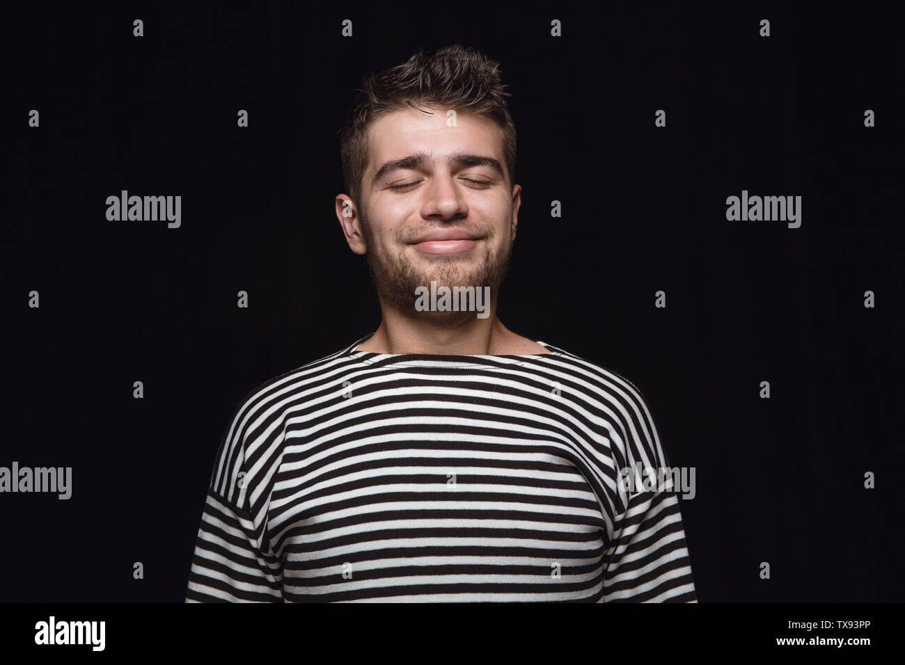 Close up portrait of young man isolated on black studio background ...