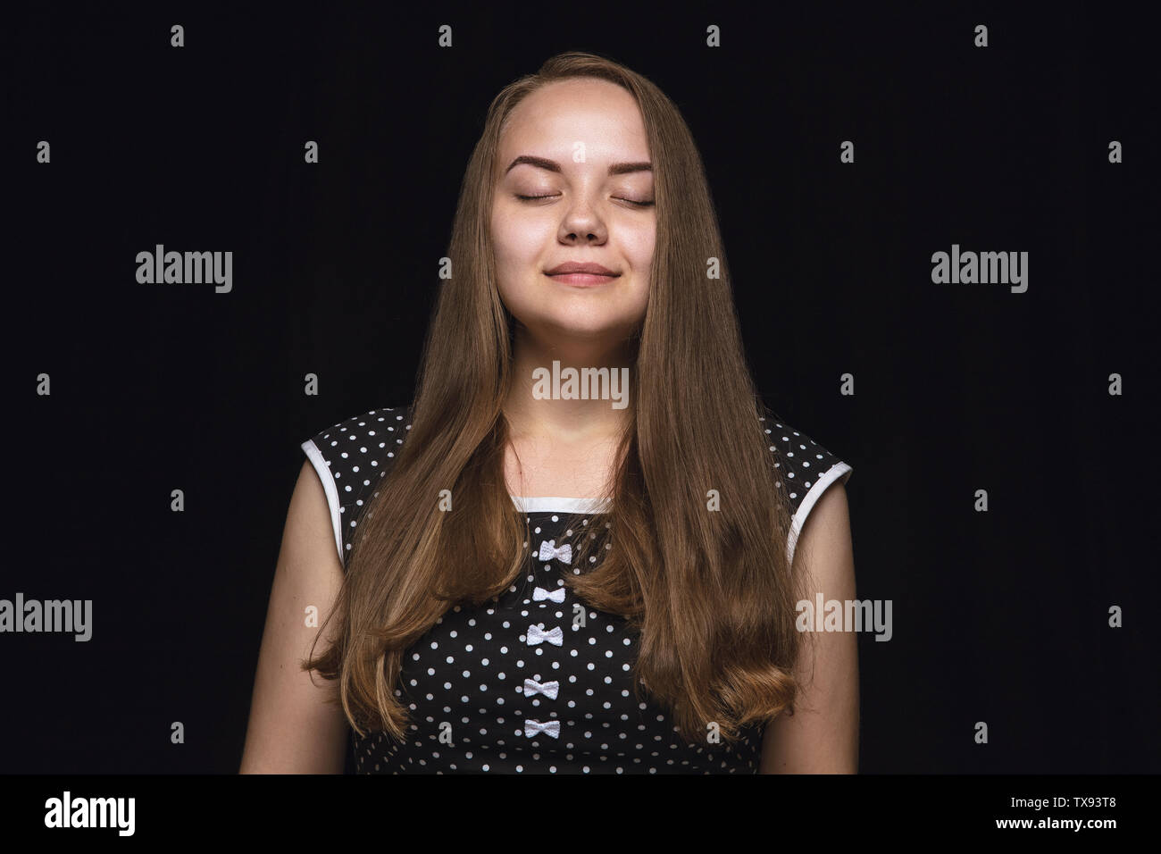Close up portrait of young woman isolated on black studio background ...