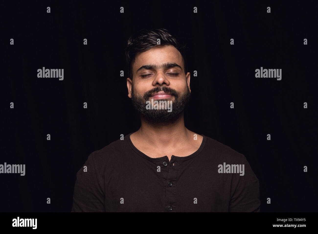 Close up portrait of young man isolated on black studio background ...