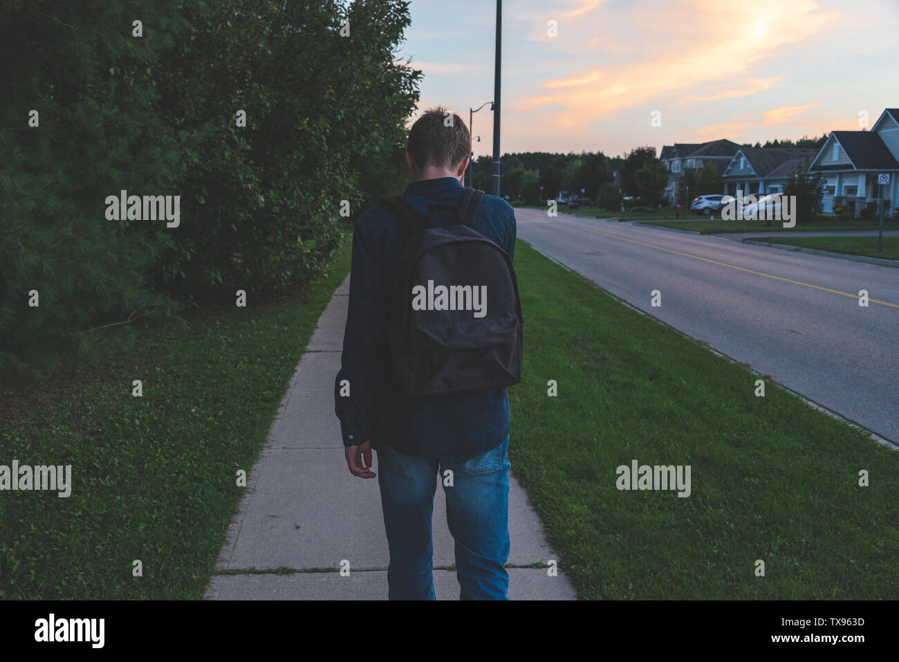 Upset teenager walking down a sidewalk at sunset Stock Photo - Alamy