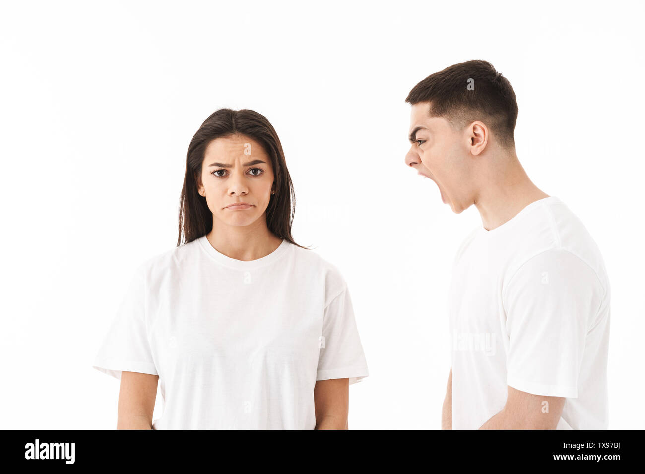 Angry young couple standing isolated over white background, having an ...