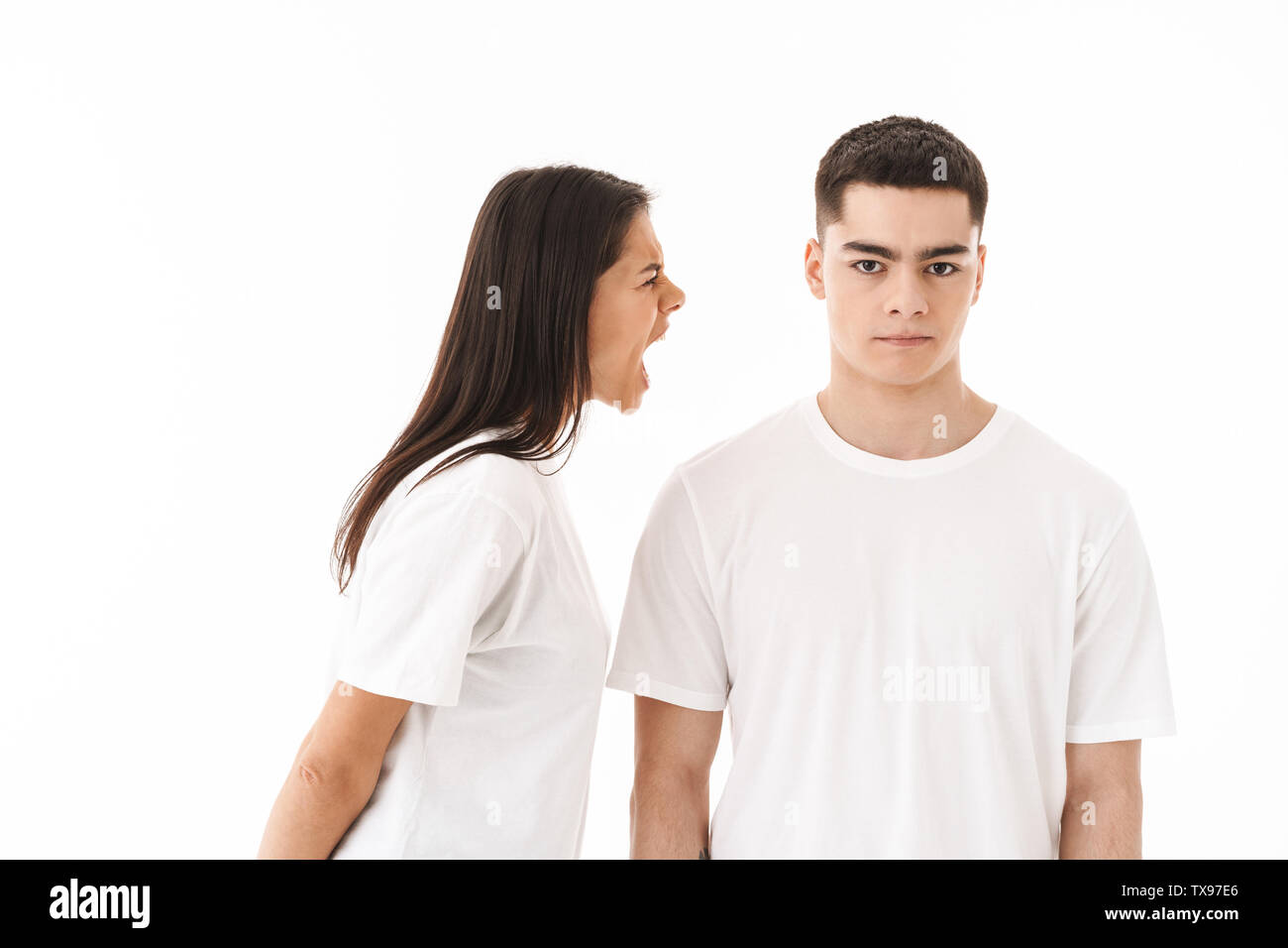 Angry young couple standing isolated over white background, having an ...