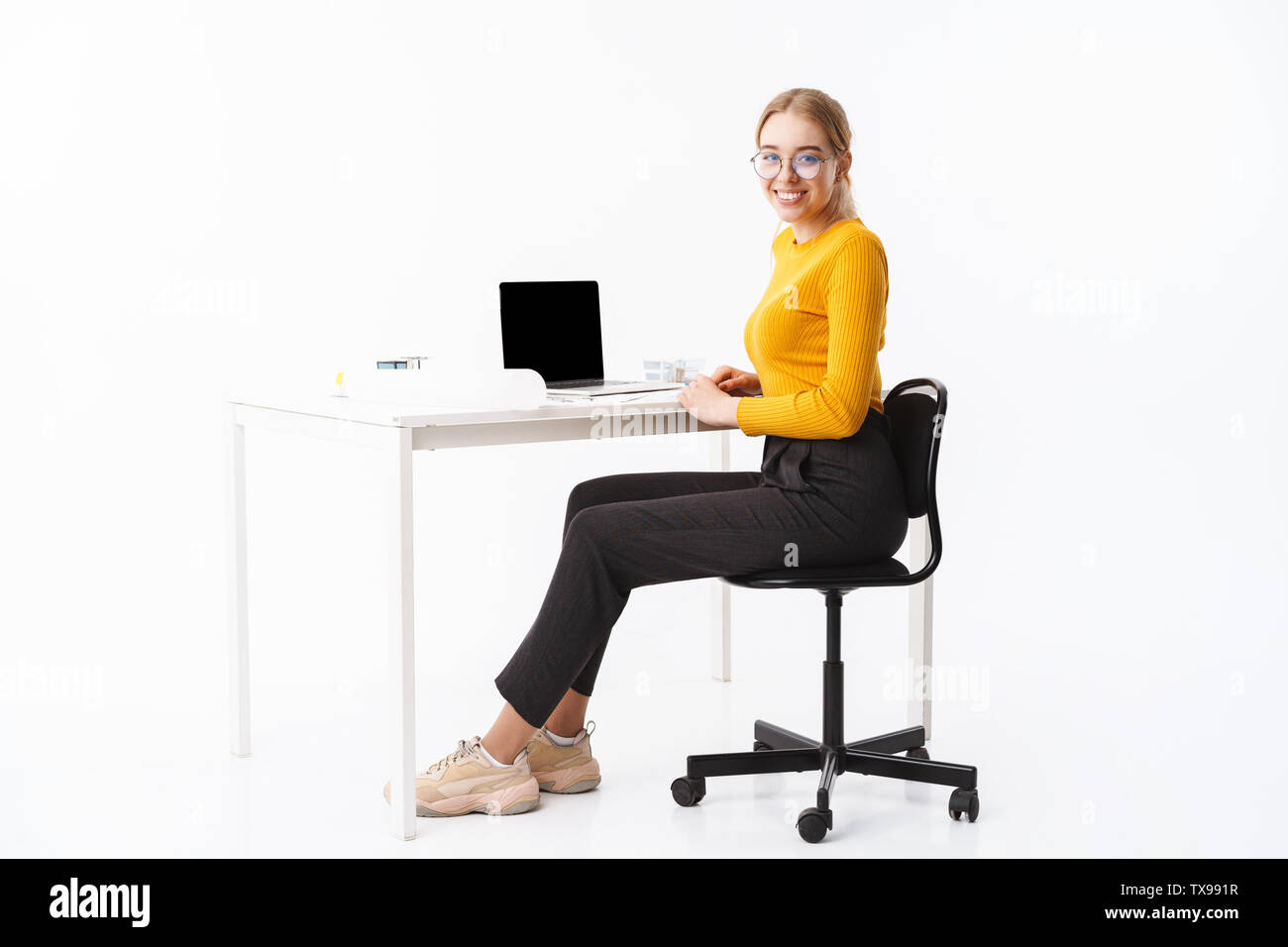 Side view of a beautiful young woman sitting at the workplace working ...