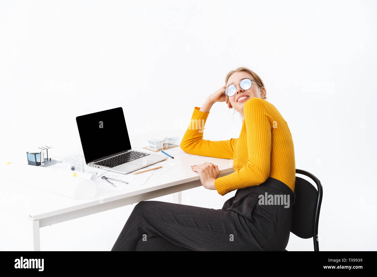Side view of a beautiful young woman sitting at the workplace working ...