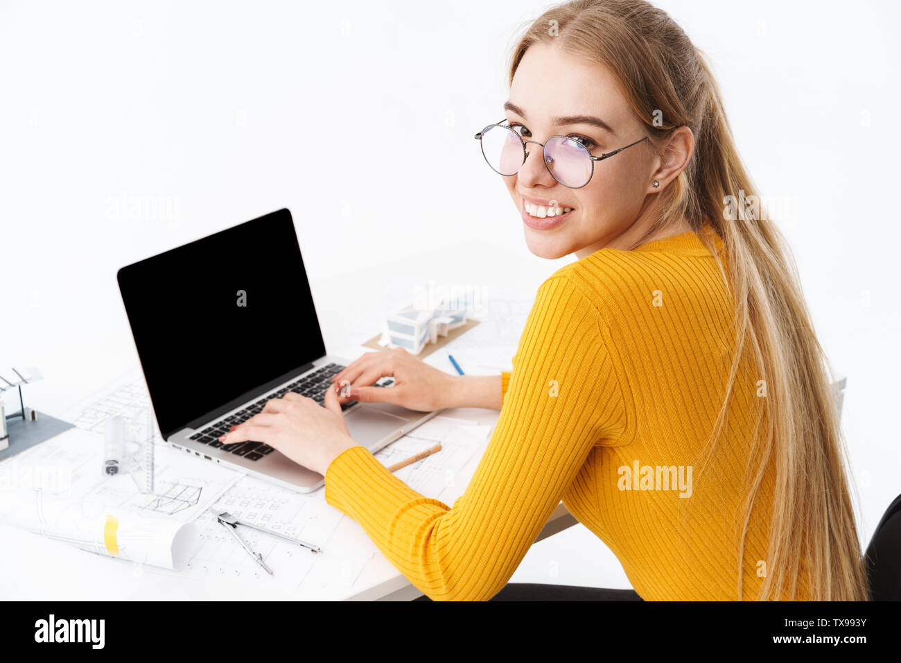 Side view of a beautiful young woman sitting at the workplace working ...