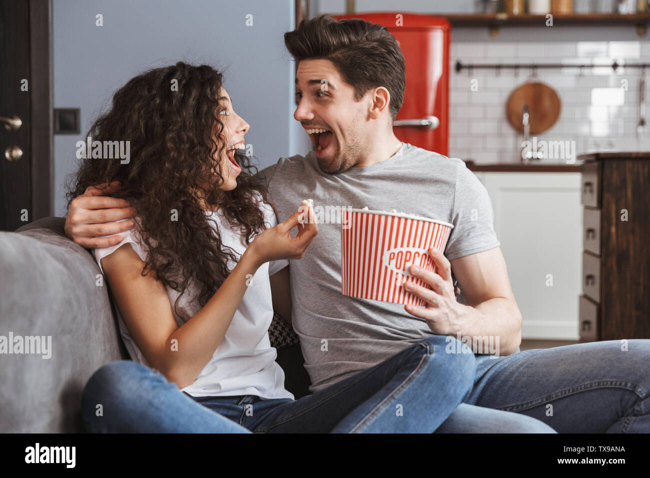 Picture of ecstatic young couple man and woman 30s sitting on sofa at ...