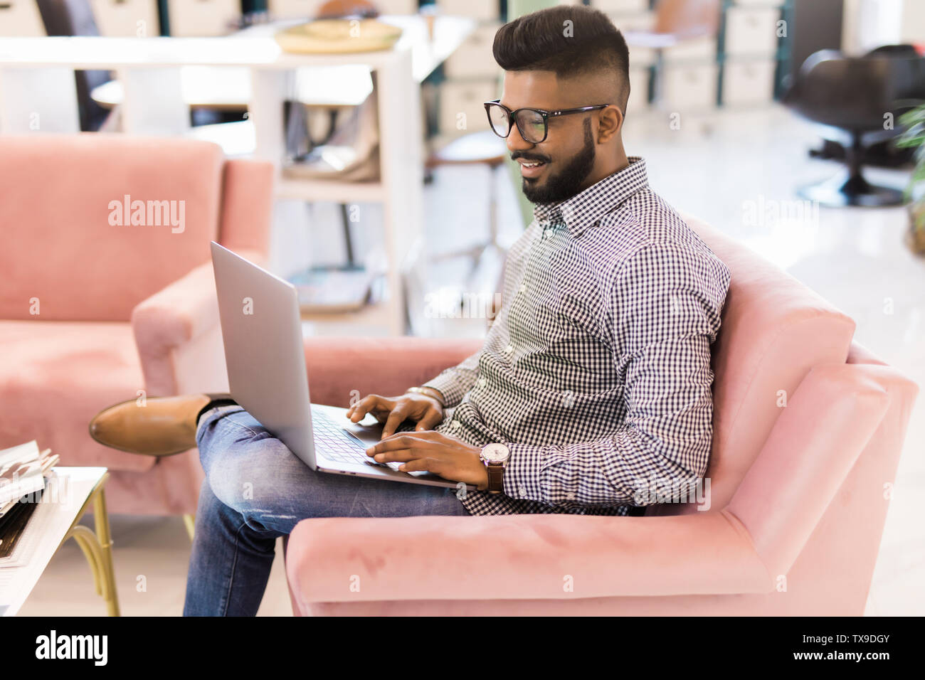 Casual young man using laptop with happy on sofa in modern office ...