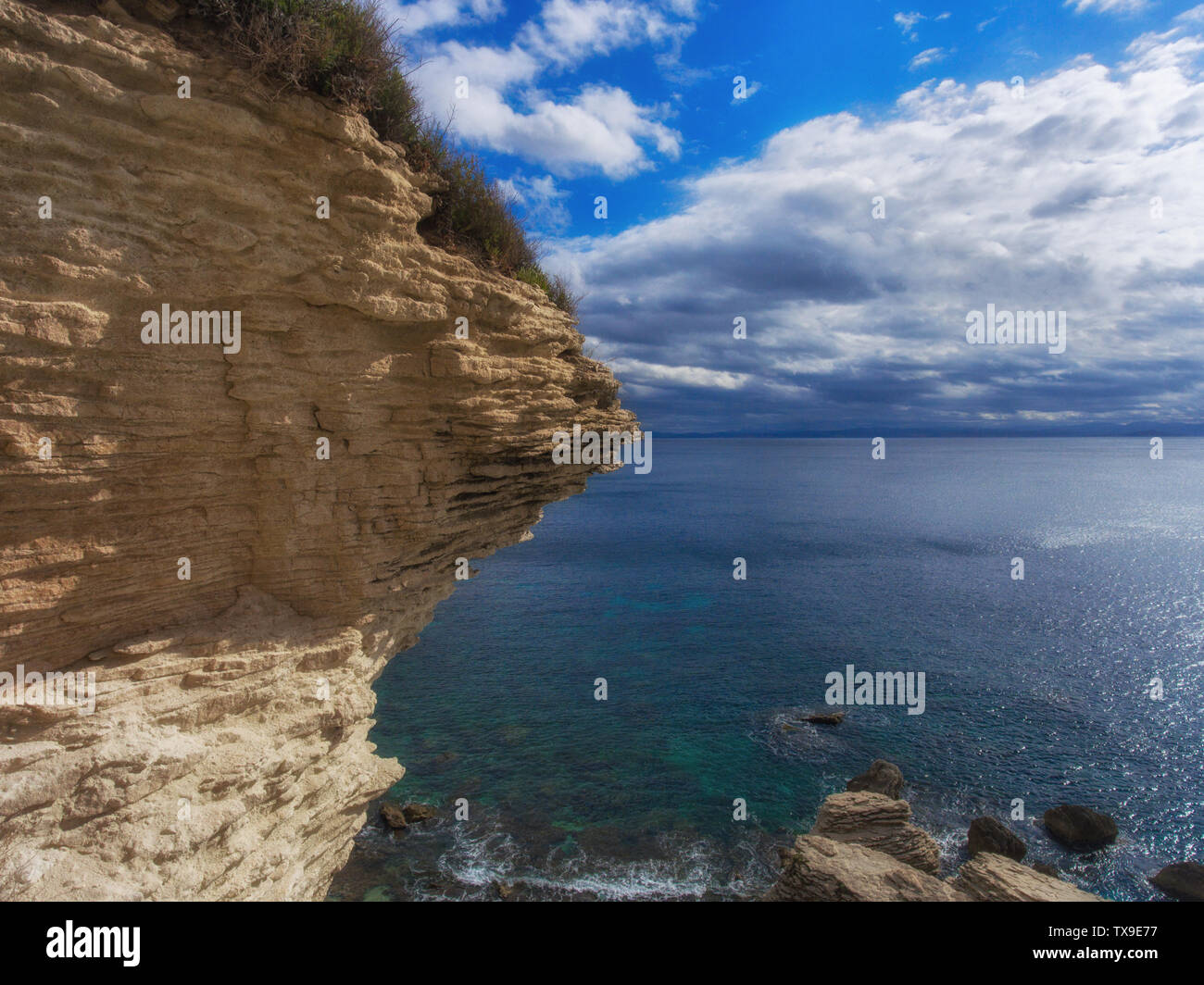 A layered piece of rock protruding above the sea Stock Photo - Alamy