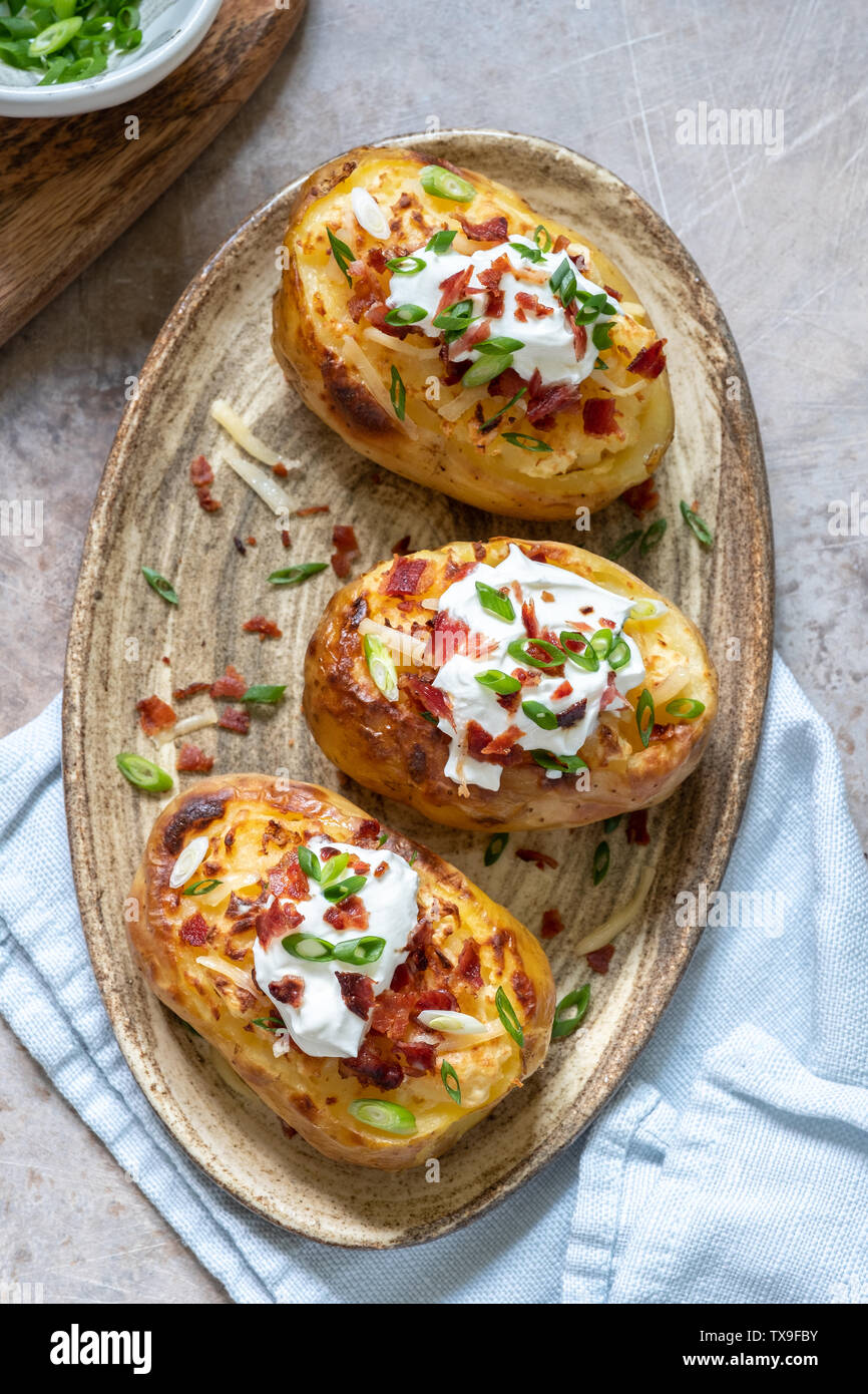 Baked loaded potato with bacon, cheese, sour cream and onion Stock ...