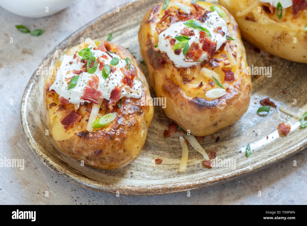 Baked loaded potato with bacon, cheese, sour cream and onion Stock ...