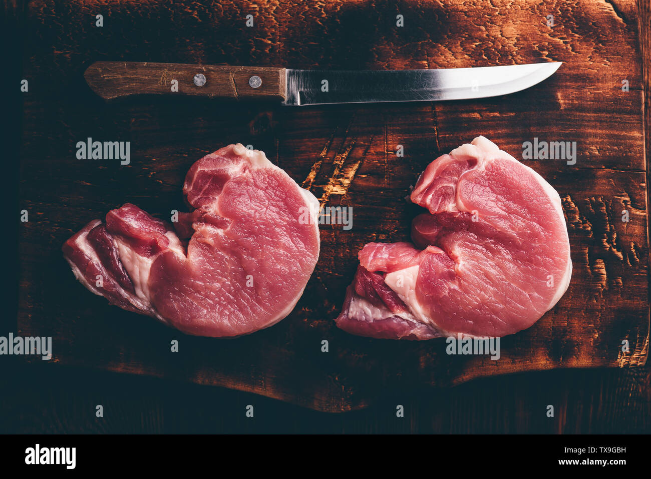 Two pork loin steaks with knife on rustic cutting board Stock Photo - Alamy