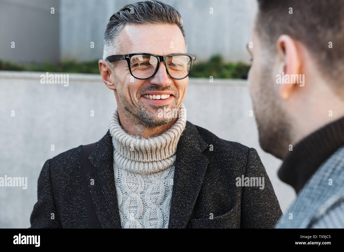 Two handsome men wearing coats spending time outdoors, talking Stock ...