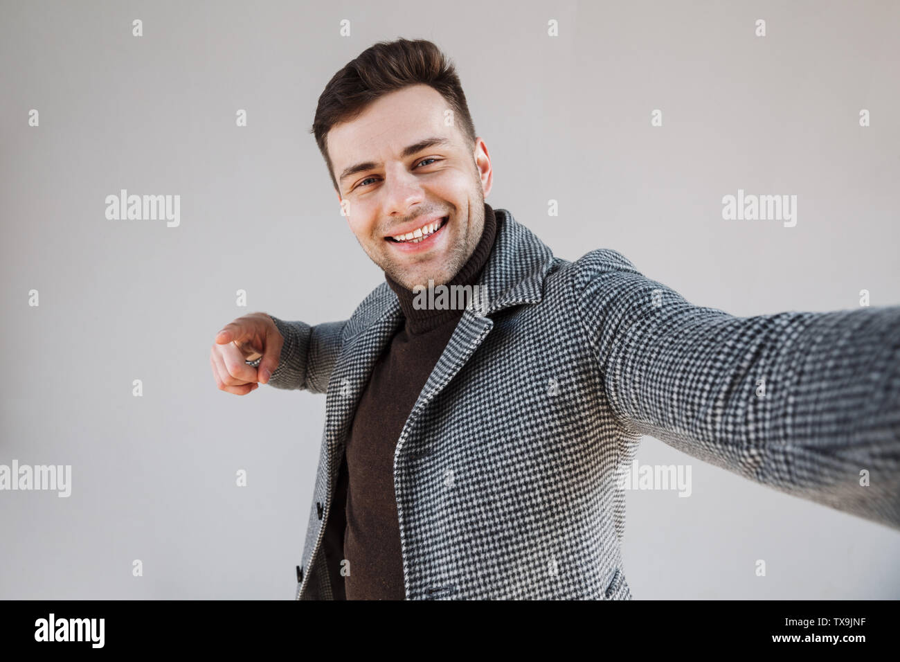 Attractive happy man wearing coat standing isolated over gray ...