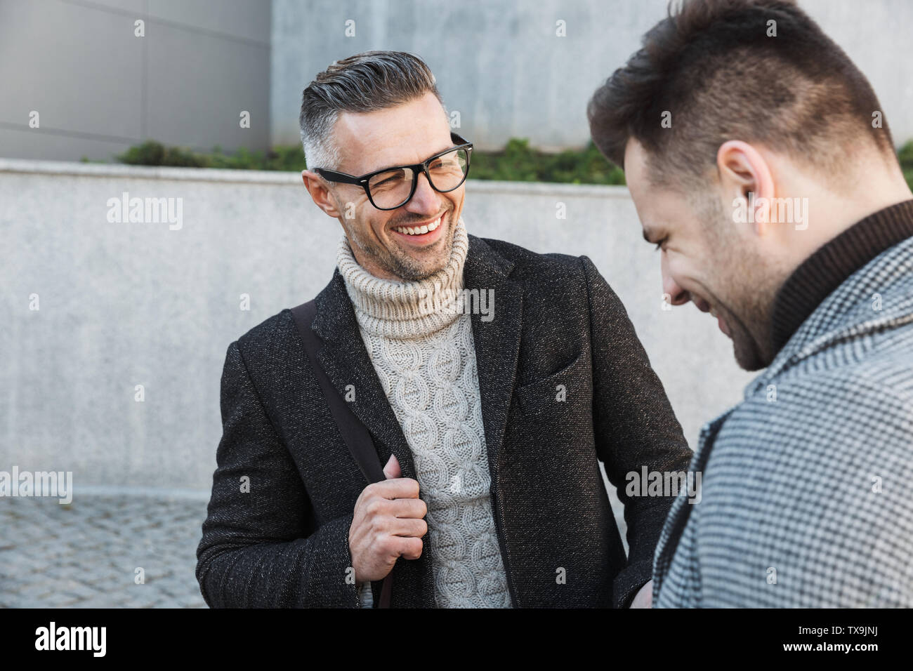 Two handsome men wearing coats spending time outdoors, talking Stock ...