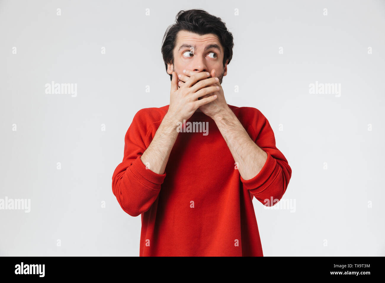 Picture of a handsome young scared man posing isolated over white wall ...