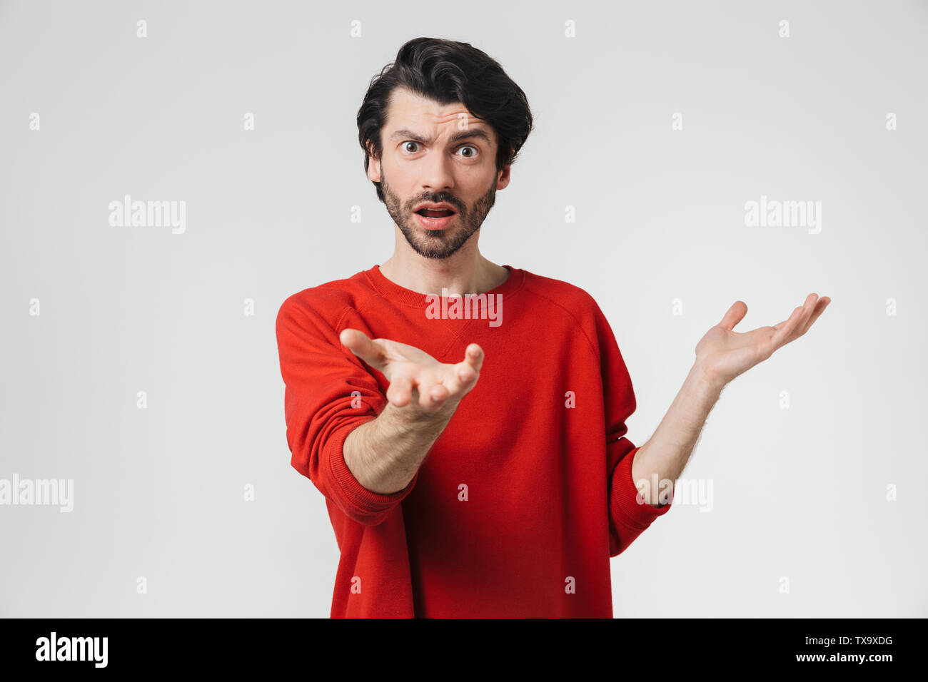 Image of a handsome confused young man isolated over white wall ...