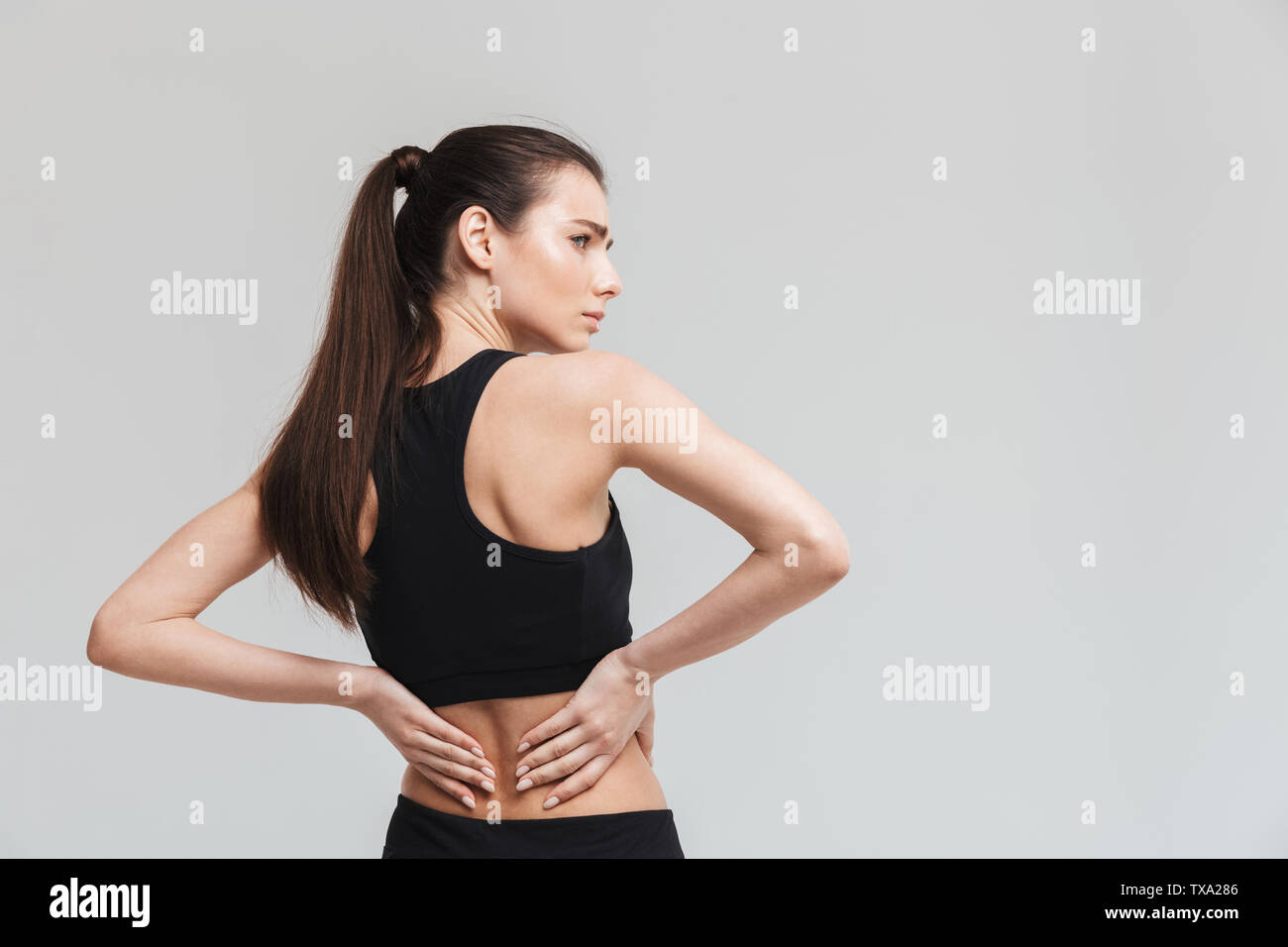 Image of a beautiful young sad sport fitness woman with backache ...