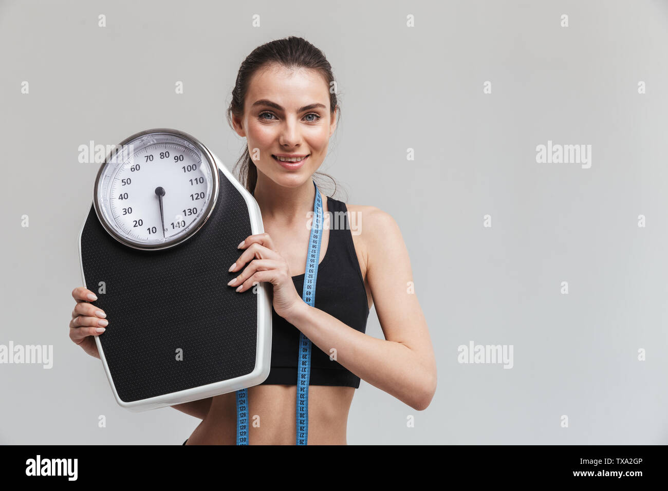 Image of a beautiful young sport fitness woman posing with scales ...