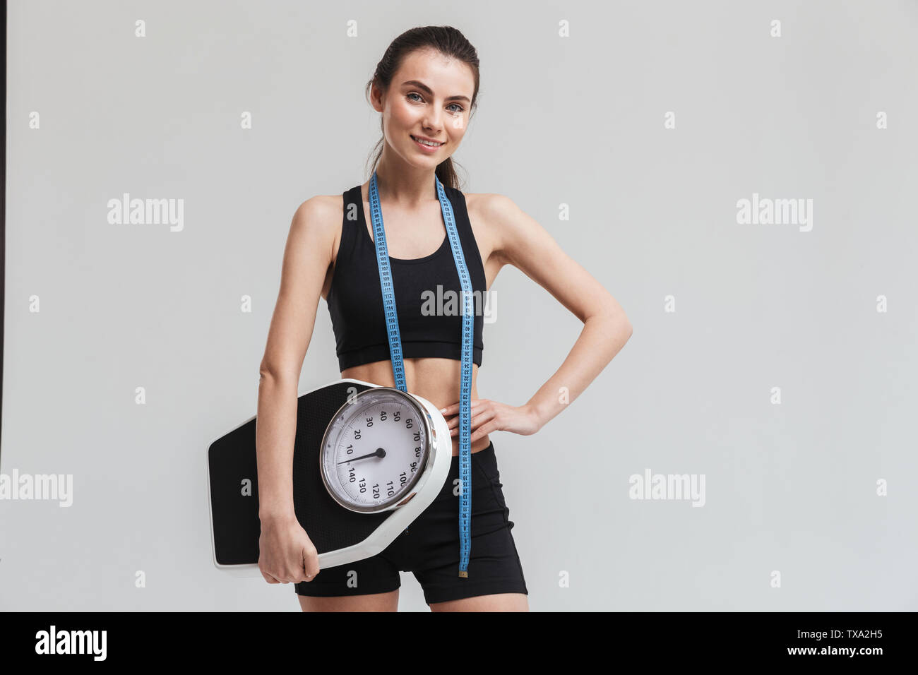 Image of a beautiful young sport fitness woman posing with scales ...
