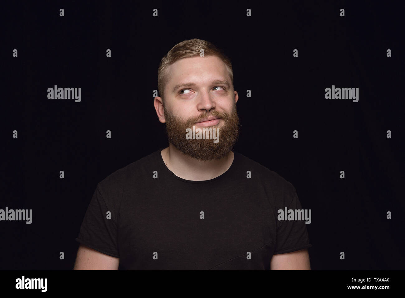 Close up portrait of young man isolated on black studio background ...