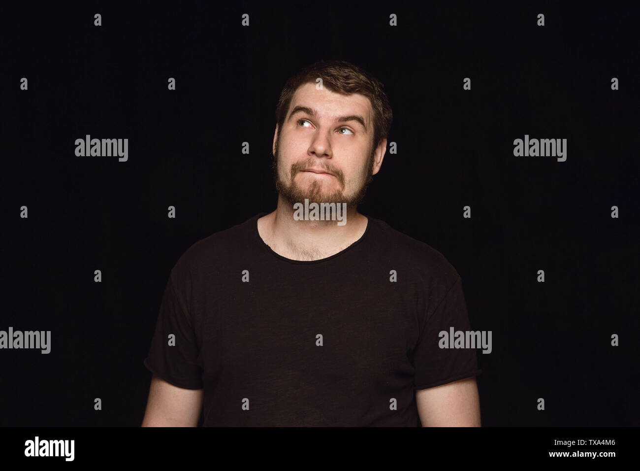 Close up portrait of young man isolated on black studio background ...