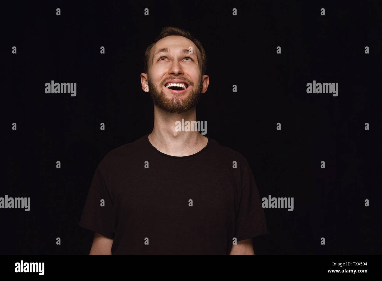Close up portrait of young man isolated on black studio background ...