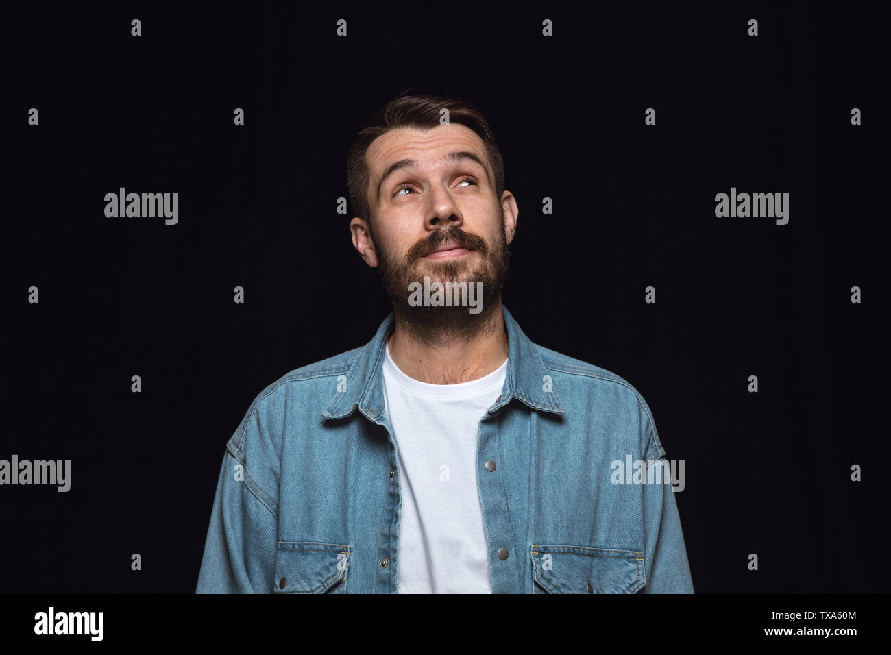 Close up portrait of young man isolated on black studio background ...