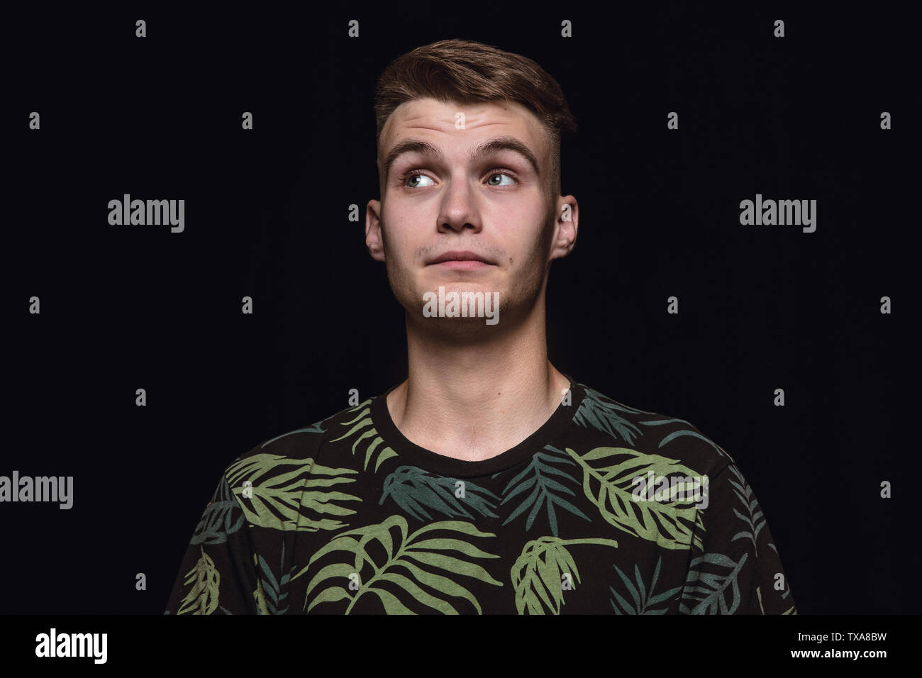 Close up portrait of young man isolated on black studio background ...
