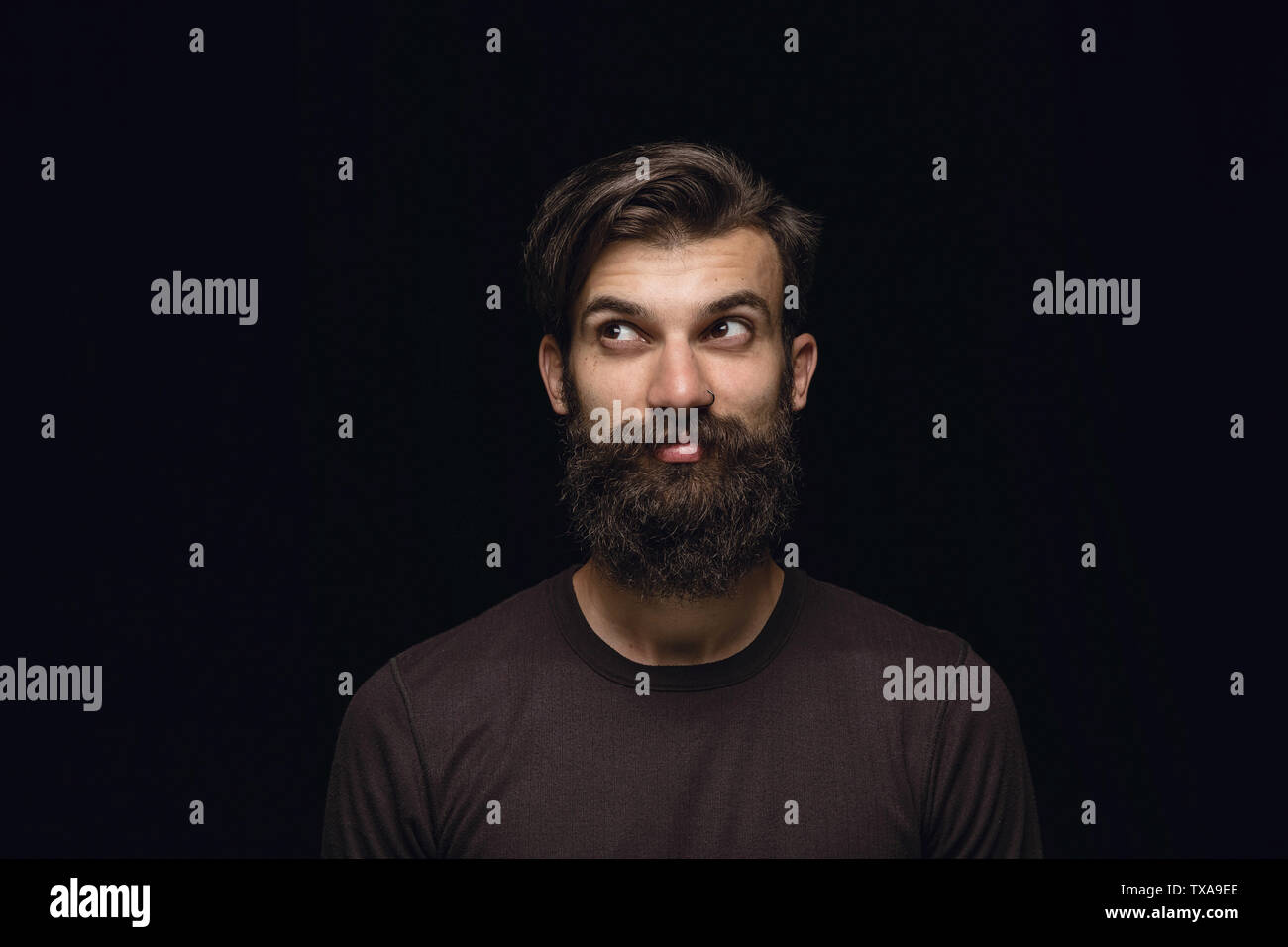 Close up portrait of young man isolated on black studio background ...