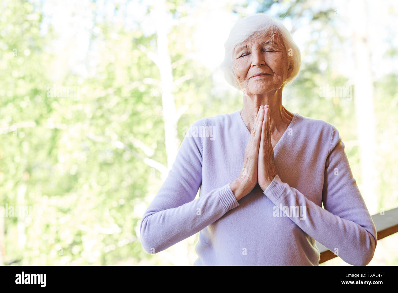 Pretty grandma in casualwear keeping her hands put together by chest ...