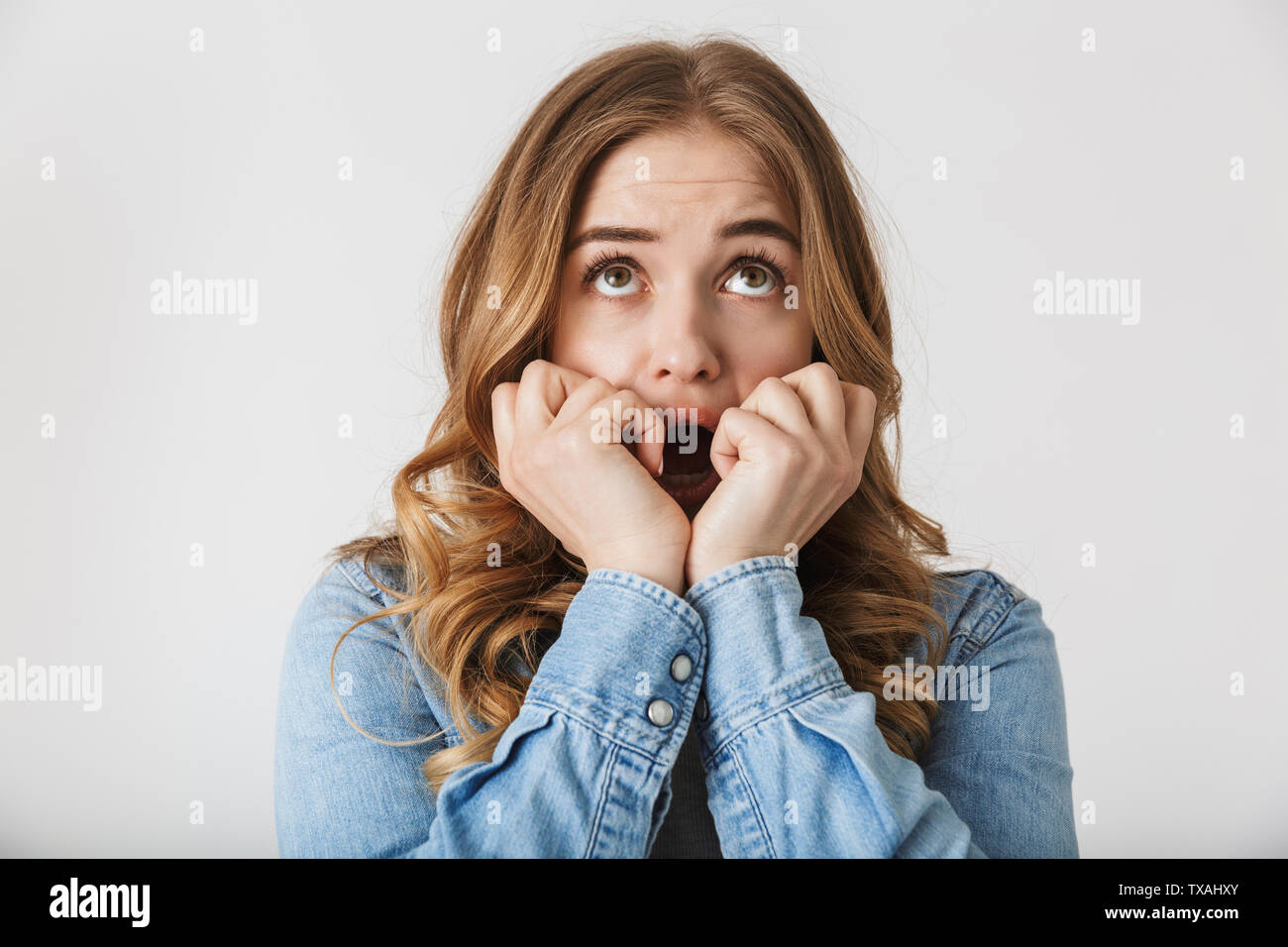 Attractive scared young girl standing isolated over white background ...